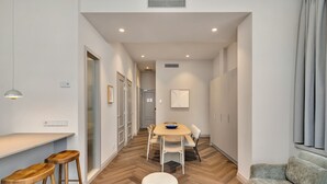 Cozinha moderna com piso de madeira em padrão herringbone, armários brancos e uma ilha central com banquetas.