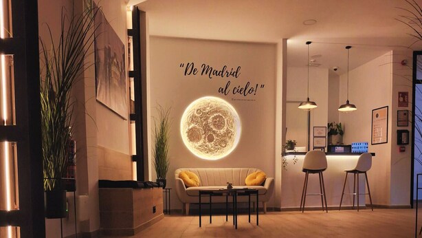 Um interior moderno com um sofá, uma escrivaninha e uma parede com ilustração da lua.