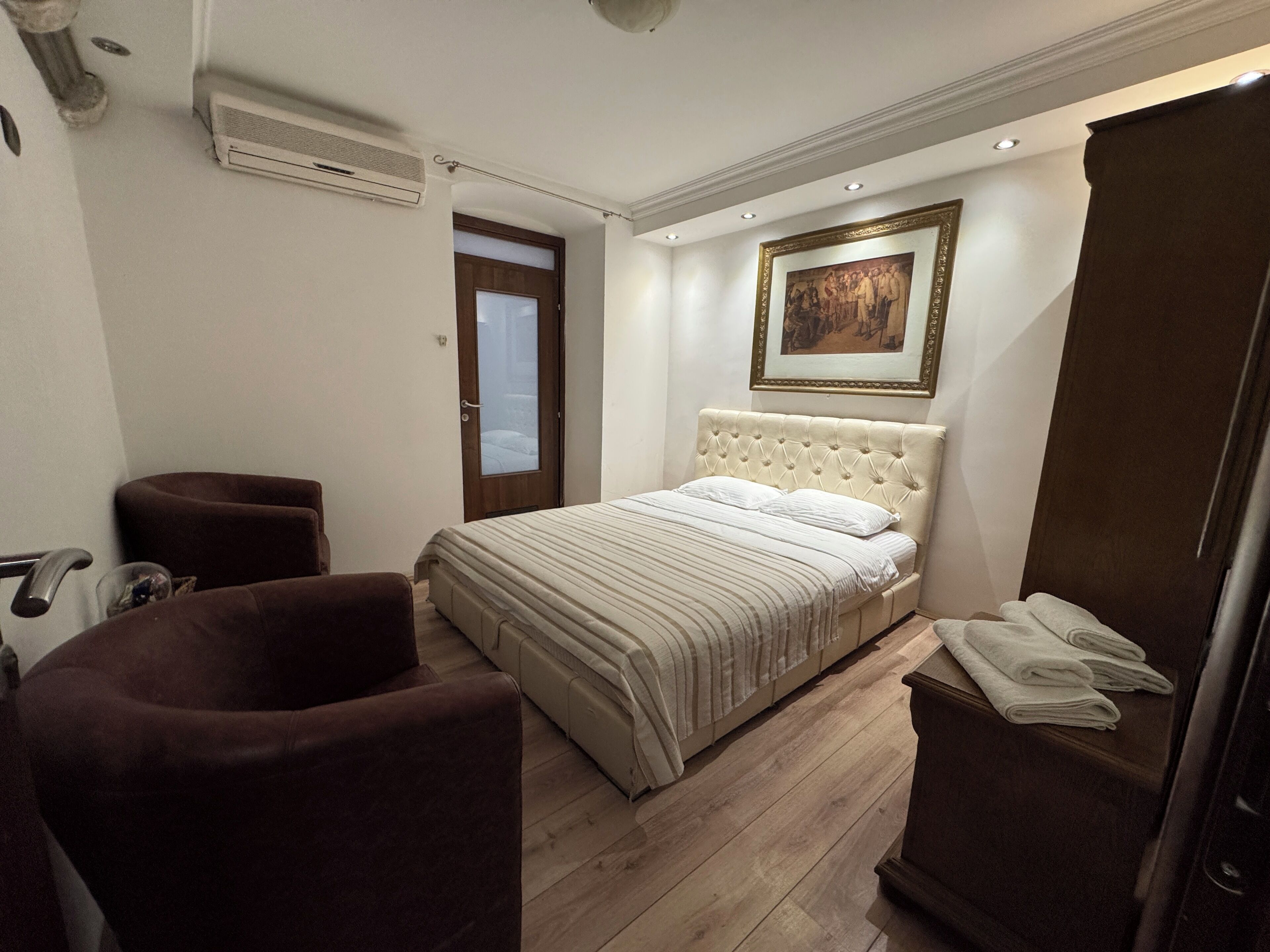 Quarto com cama, cadeira, guarda-roupa e porta.