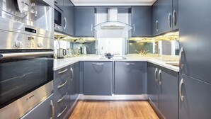 Uma cozinha moderna com eletrodomésticos de aço inoxidável, armários cinzas e piso de madeira.