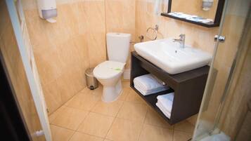 Casa de banho moderna com sanita, lavatório e cabine de duche em vidro.