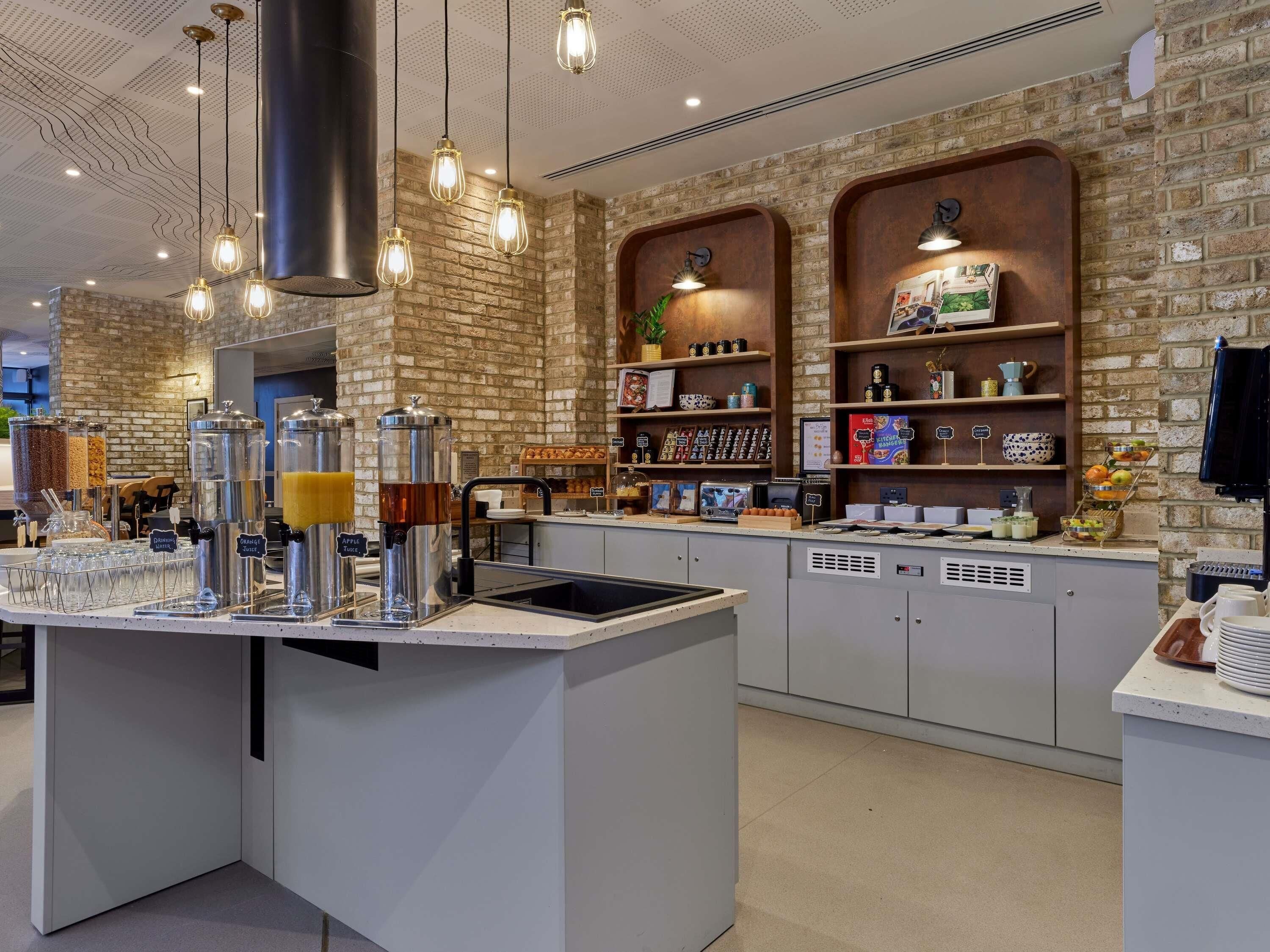 Um café com parede de tijolos, um balcão de café e diversos produtos alimentares nas prateleiras.