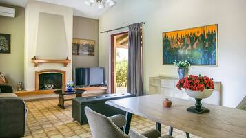 Uma sala de estar com lareira, televisão, mesa de jantar e um quadro grande na parede.
