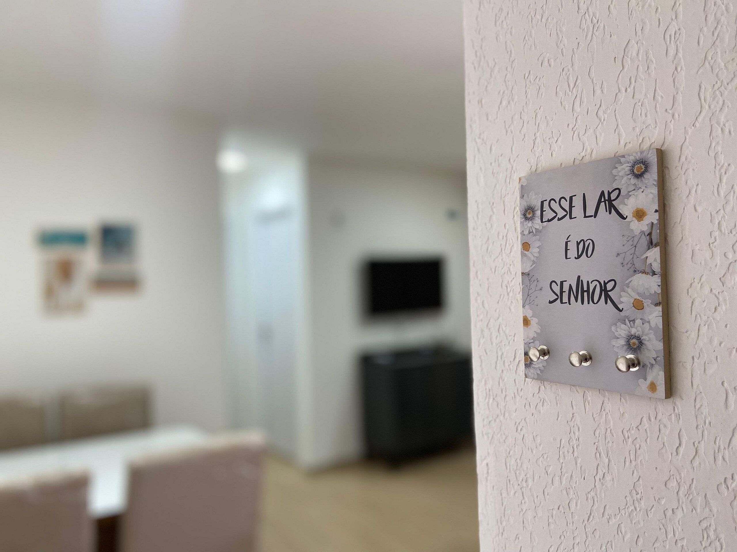 Quarto com um aviso fixado na parede, uma televisão e uma porta ao fundo.