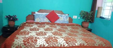 Quarto com uma cama, duas mesas de cabeceira, uma janela e um vaso com planta.