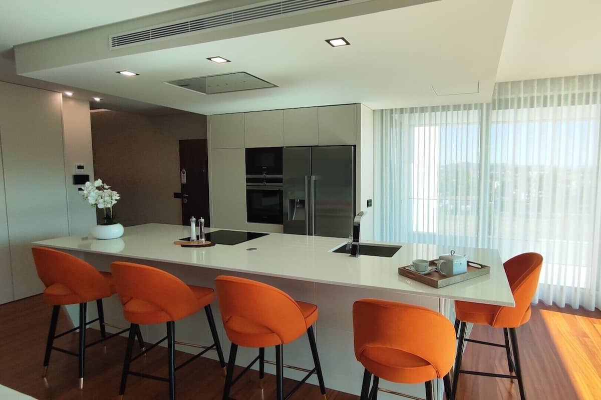 Cozinha moderna com ilha central, banquetas e vista da cidade através de grandes janelas.