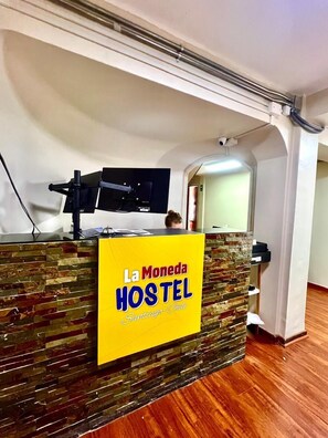 Uma receção com um letreiro amarelo a indicar "La Moneda HOSTEL Santiago-Chile".