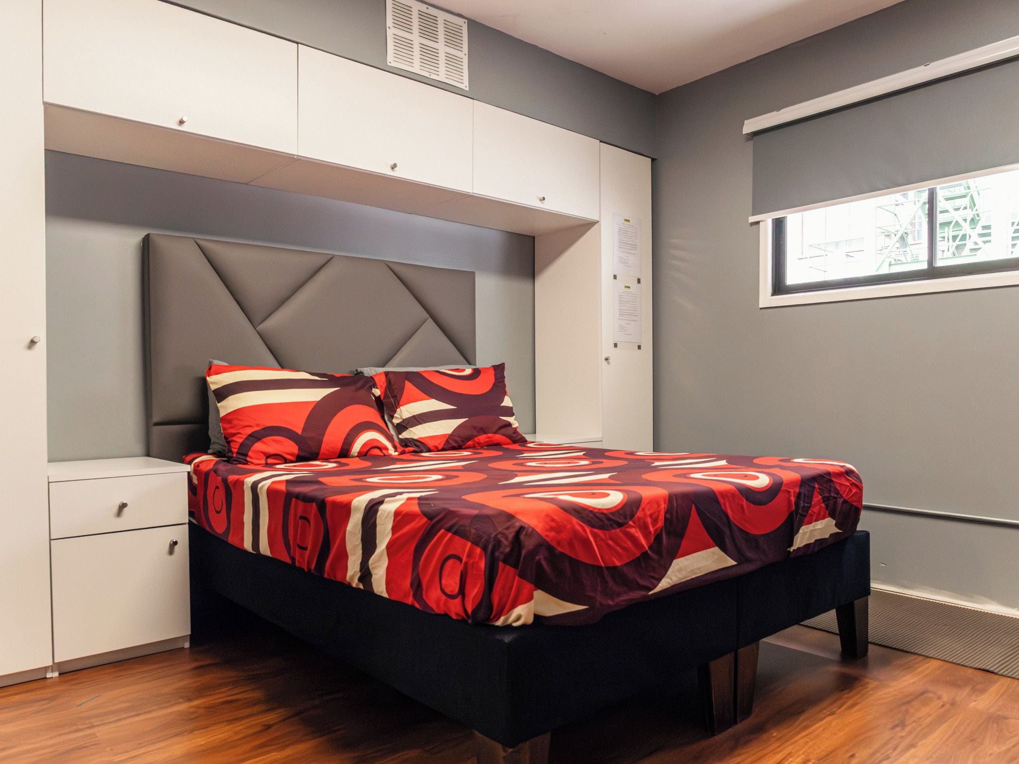 Quarto com cama, mesa de cabeceira, armário embutido e janela.