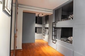 Um corredor estreito com piso de madeira que leva a um quarto com beliches.