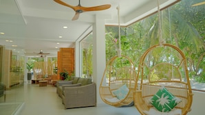 Um quarto espaçoso com uma janela grande, uma cadeira suspensa e um sofá.