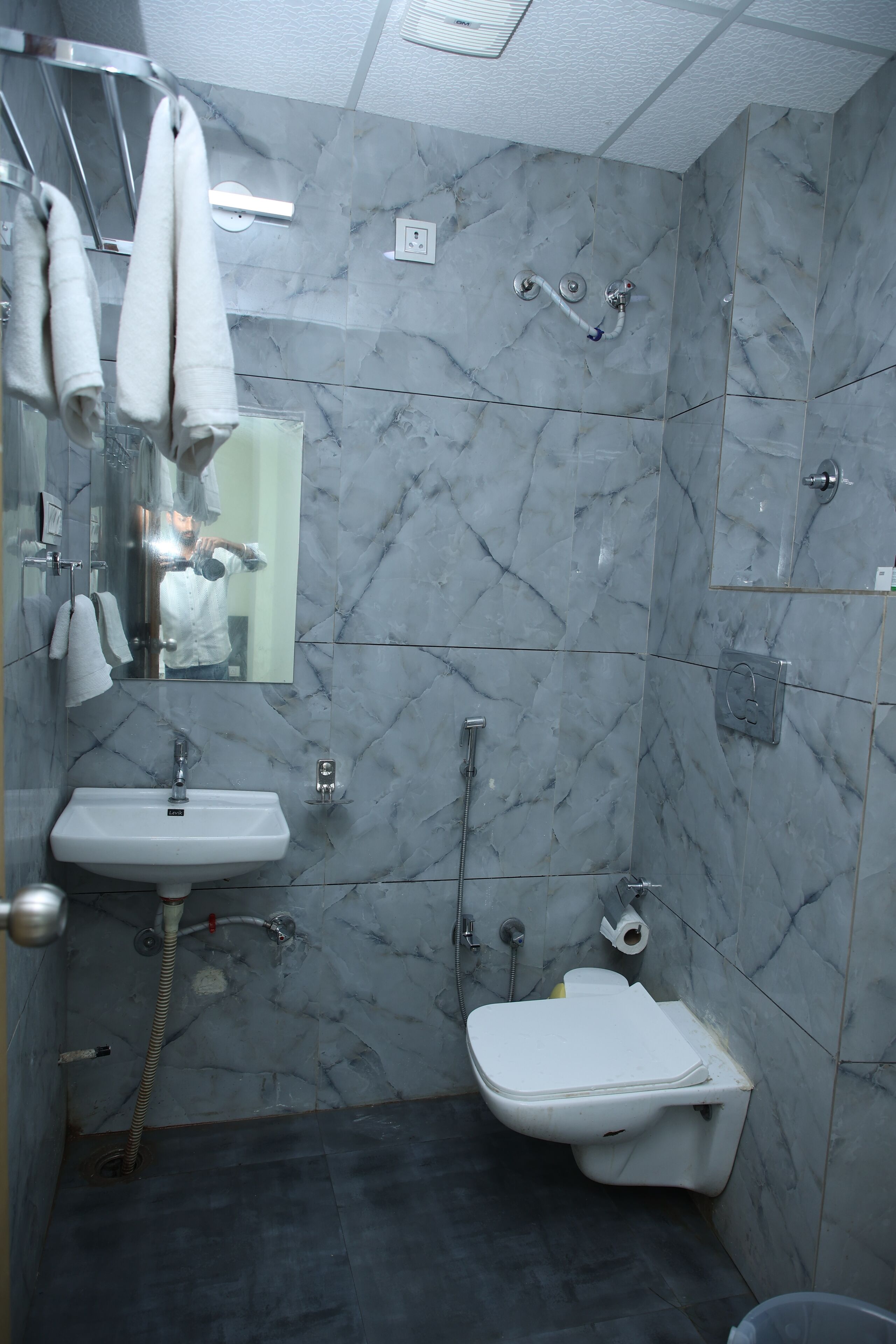 Um banheiro com pia, espelho, porta-toalhas, vaso sanitário e chuveiro.