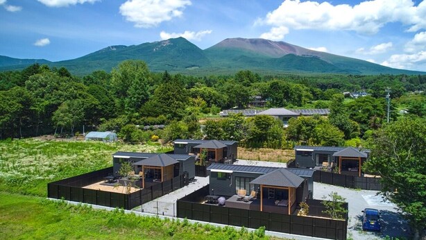 Um resort moderno e sustentável com várias cabanas, painéis solares e um exuberante cenário florestal.