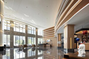 Um hall amplo com teto alto, grandes janelas e uma área de recepção com design moderno.