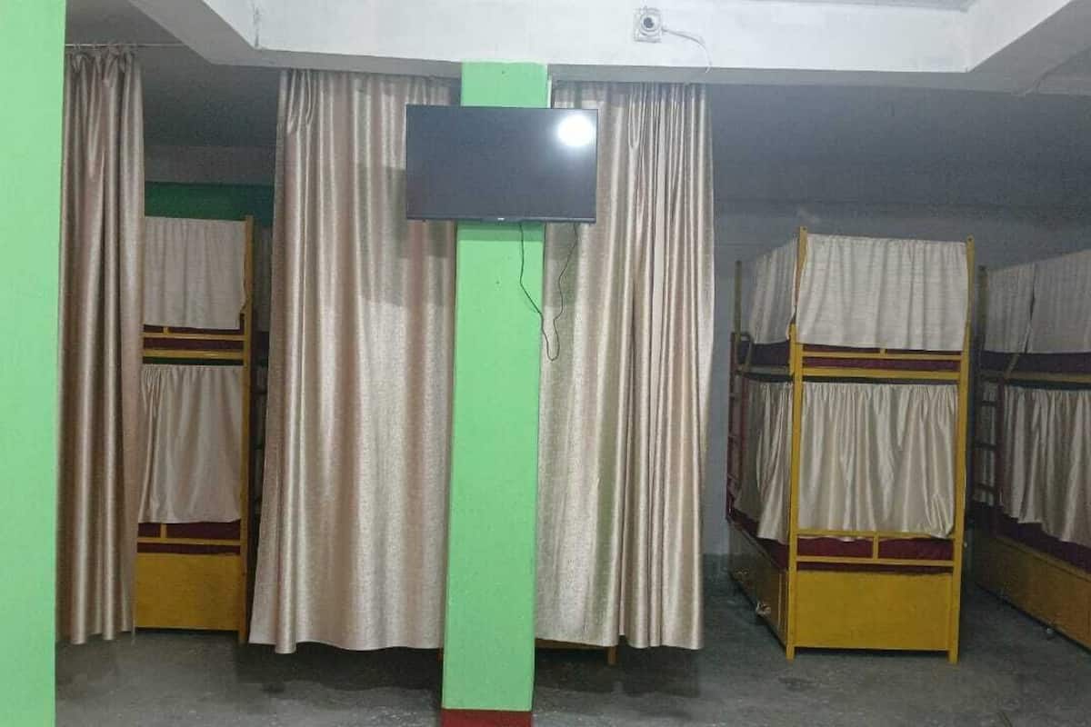 Quarto de dormitório com beliches, cortinas e uma televisão.