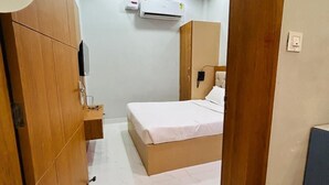 Quarto com cama, guarda-roupa de madeira, ventilador de teto, ar condicionado e televisão.