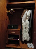 Um guarda-roupa de madeira com micro-ondas, uma gavetinha e um par de chinelos.