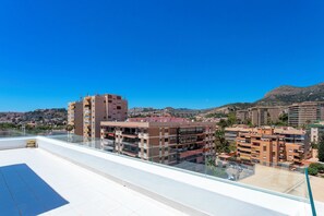 Terraço no telhado com vista clara dos edifícios ao redor e uma montanha ao fundo.