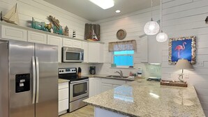 Uma cozinha moderna com eletrodomésticos de aço inoxidável, bancada de granito e objetos decorativos.