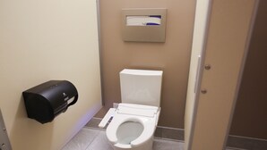 Uma casa de banho pequena e moderna com sanita branca, dispensador de papel e outro dispensador de papel fixado na parede.