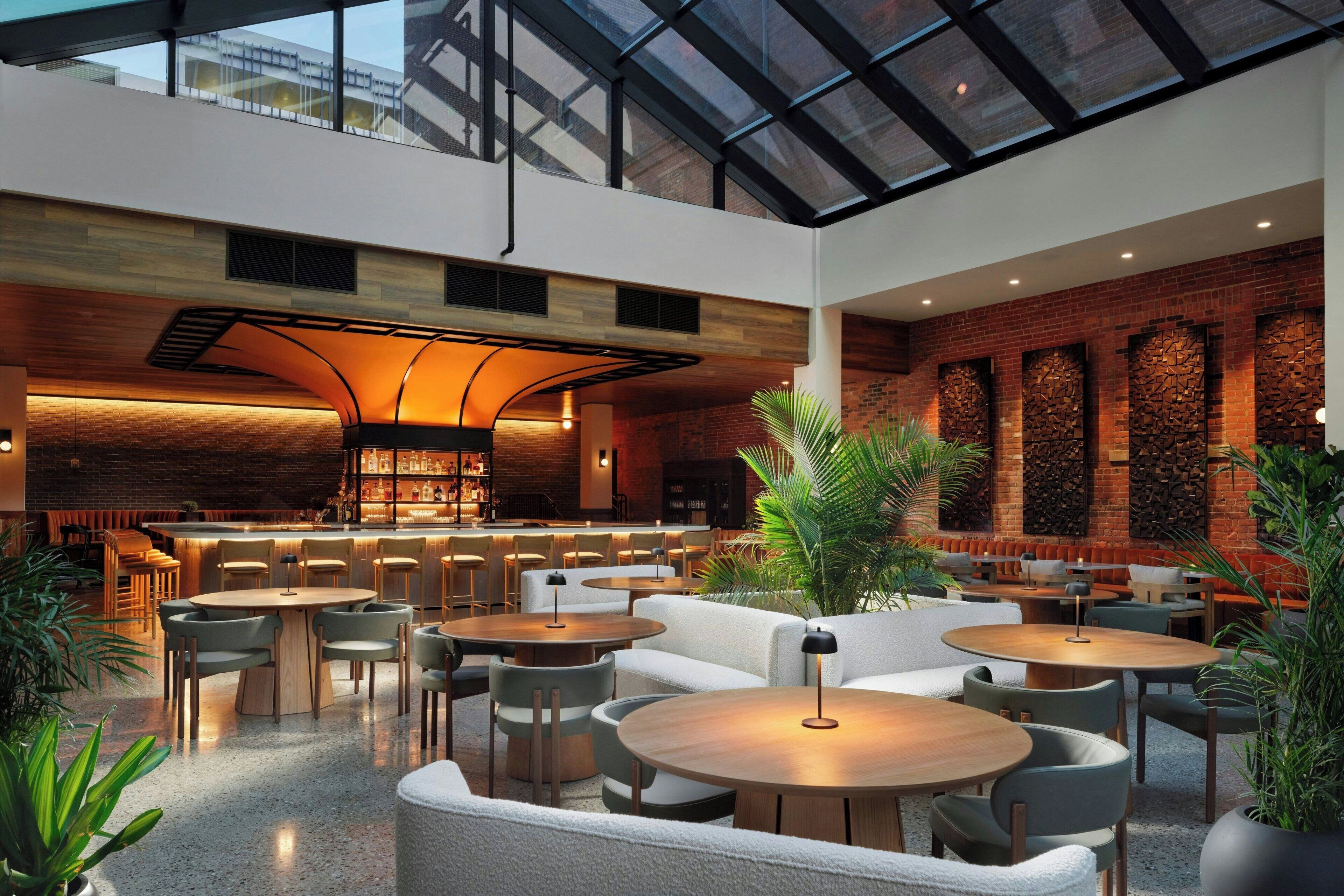 Um espaço interior moderno com área de bar, assentos e teto alto com claraboias.