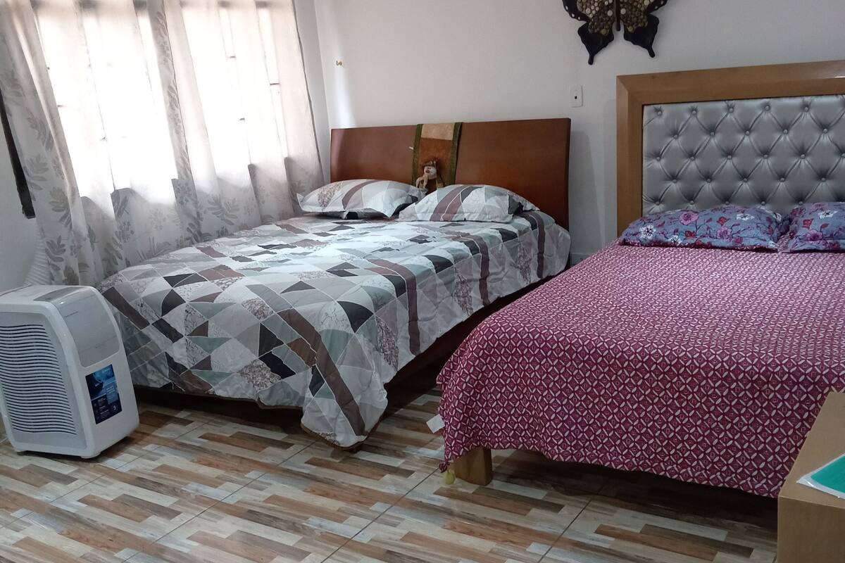 Quarto com duas camas, aquecedor, decoração de borboleta na parede e janela com cortinas.