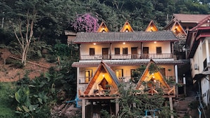 Um edifício de vários andares com arquitetura tradicional, apresentando uma varanda no andar superior e uma escadaria que leva à entrada.