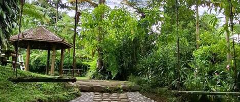 Um gazebo em um jardim exuberante, com um caminho de pedra que o leva até ele.