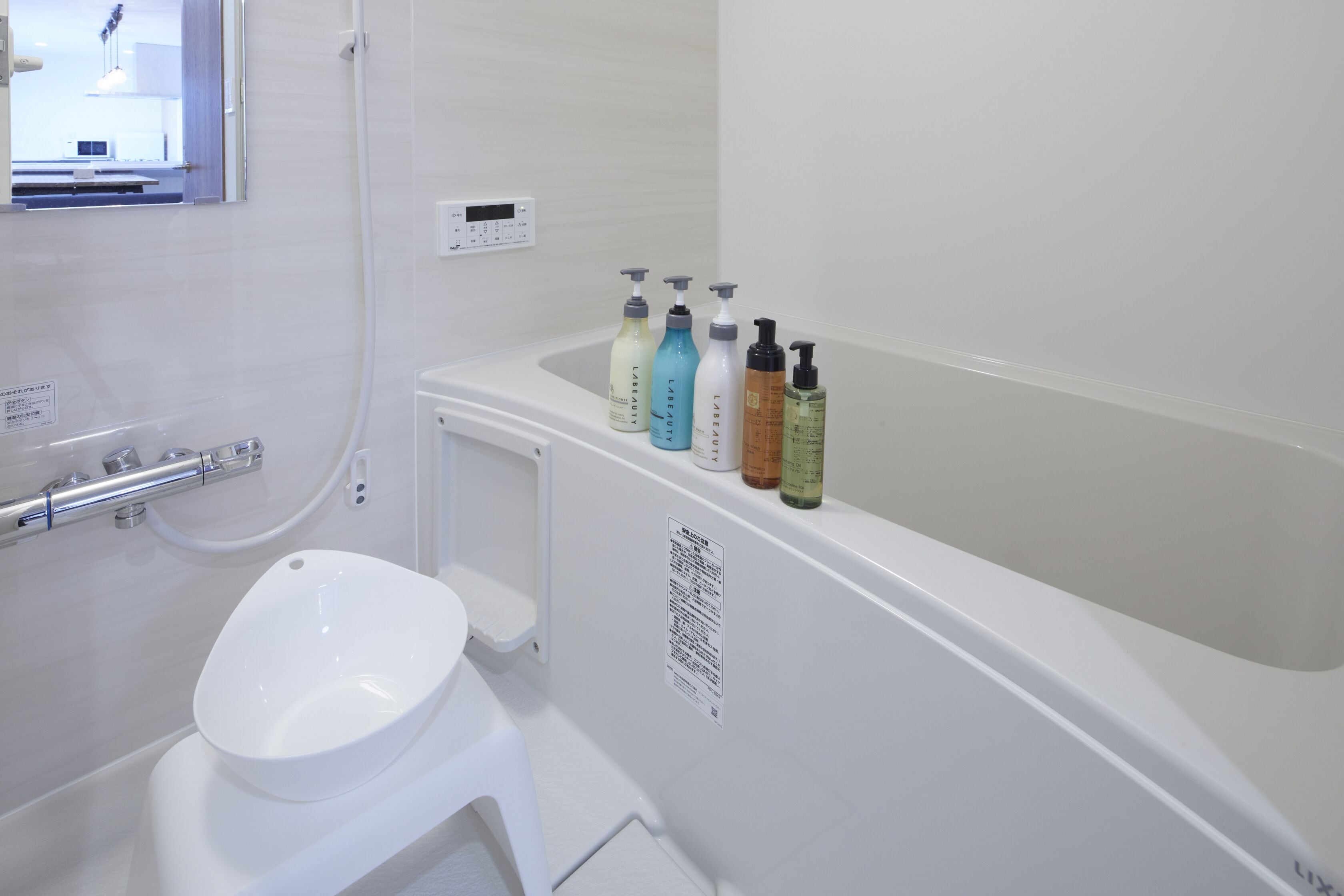 Casa de banho moderna com sanita branca, lavatório e banheira. Existem várias embalagens de produtos de higiene pessoal na borda da banheira.