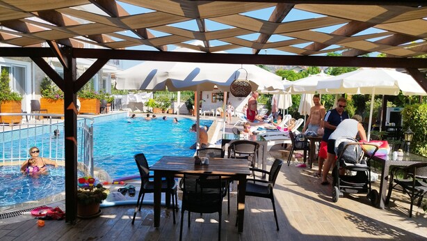 Uma área de piscina com deck de madeira, espreguiçadeiras e guarda-sóis.