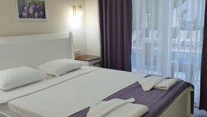 Quarto de hotel com uma cama, mesa de cabeceira, pintura e janela com cortinas.