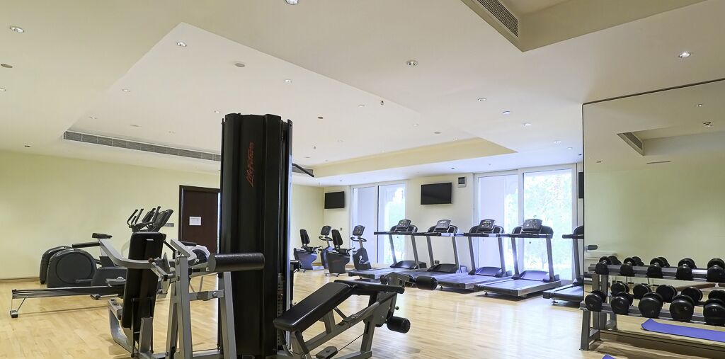 Uma academia com equipamentos de cardio, aparelhos de musculação e halteres.