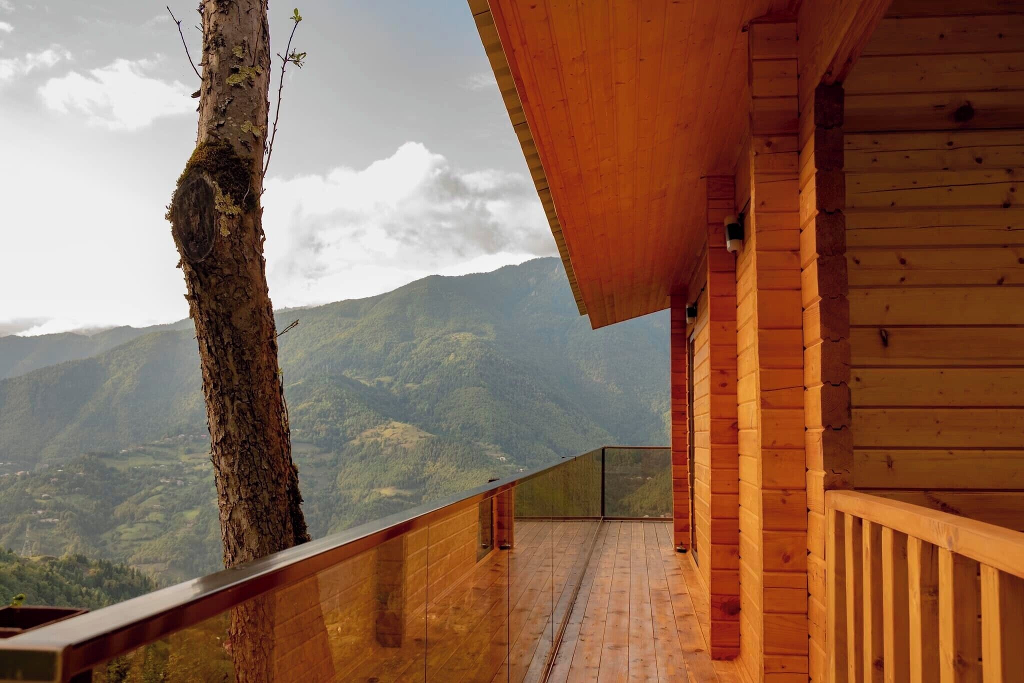 Uma cabana de madeira com varanda e vista para uma paisagem montanhosa.