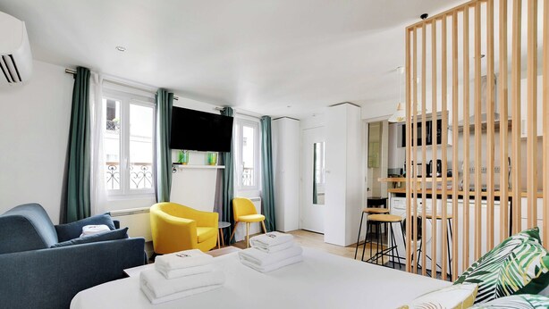 Quarto de hotel moderno com cama, sofá, escrivaninha e cadeira.