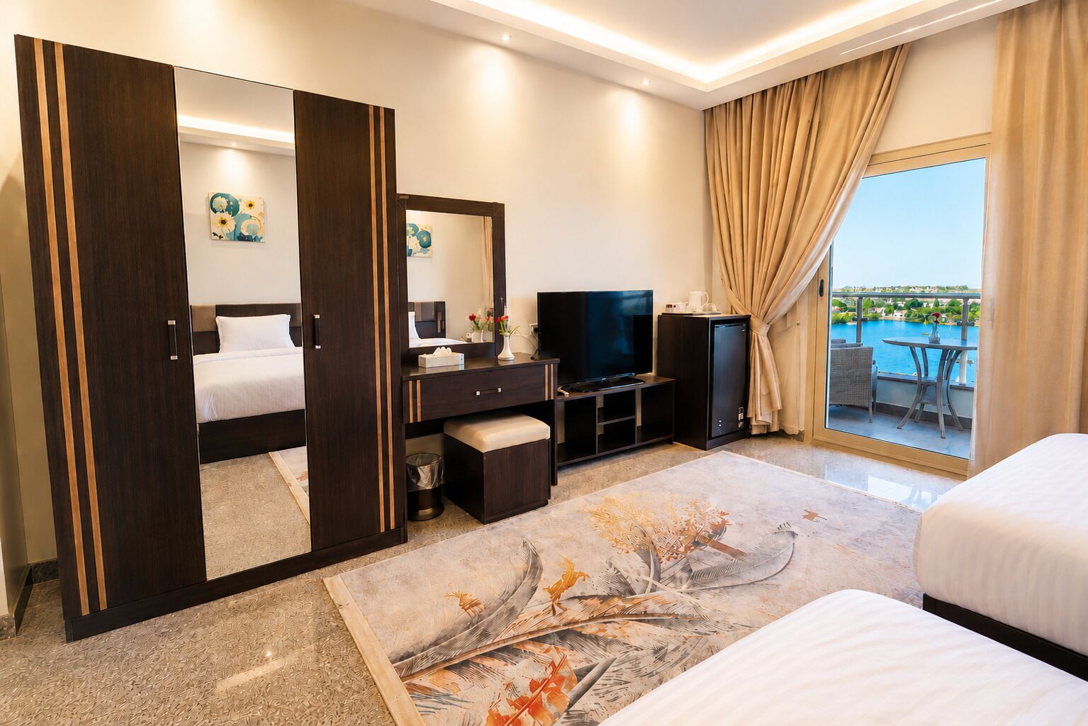 Quarto de hotel com cama, televisão, escrivaninha com computador, espelho e vista para o mar.