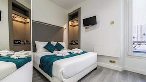Quarto de hotel moderno com uma cama grande, TV na parede e vista para a varanda.