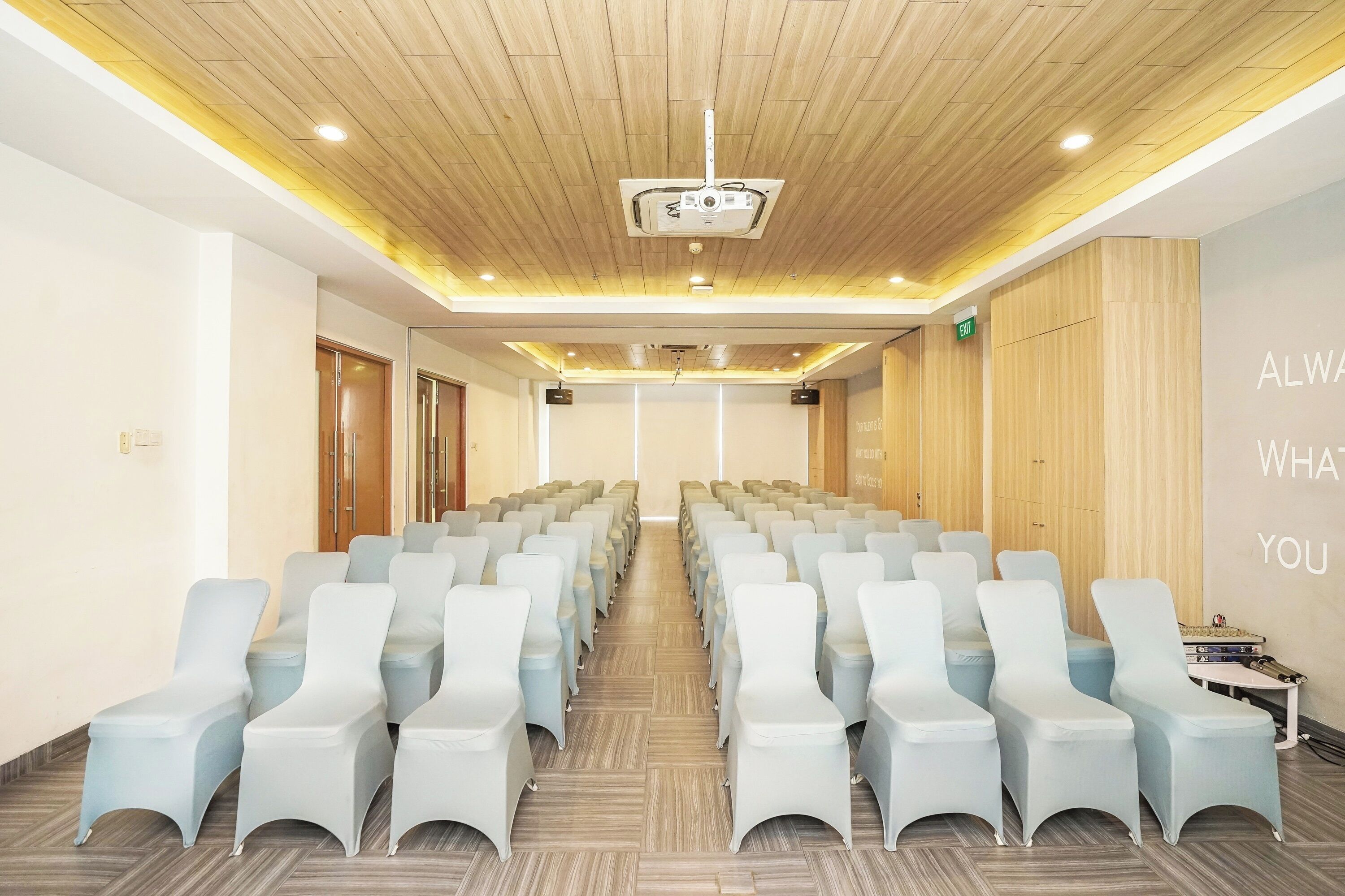Uma sala de conferências com fileiras de cadeiras, um projetor e teto de madeira.