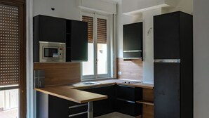 Cozinha moderna com bancada de madeira, eletrodomésticos embutidos e janela com persianas.