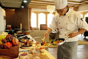 Um chef preparando comida em uma cozinha bem iluminada, com detalhes em madeira e eletrodomésticos modernos.
