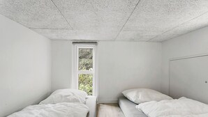 Quarto com duas camas de solteiro, uma janela e uma porta.