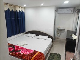 Quarto com cama, mesa de cabeceira, pia pequena e ar-condicionado.