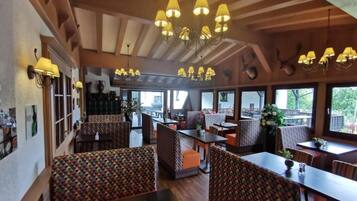 Um restaurante com vigas de madeira, cabines estampadas e luminárias pendentes.