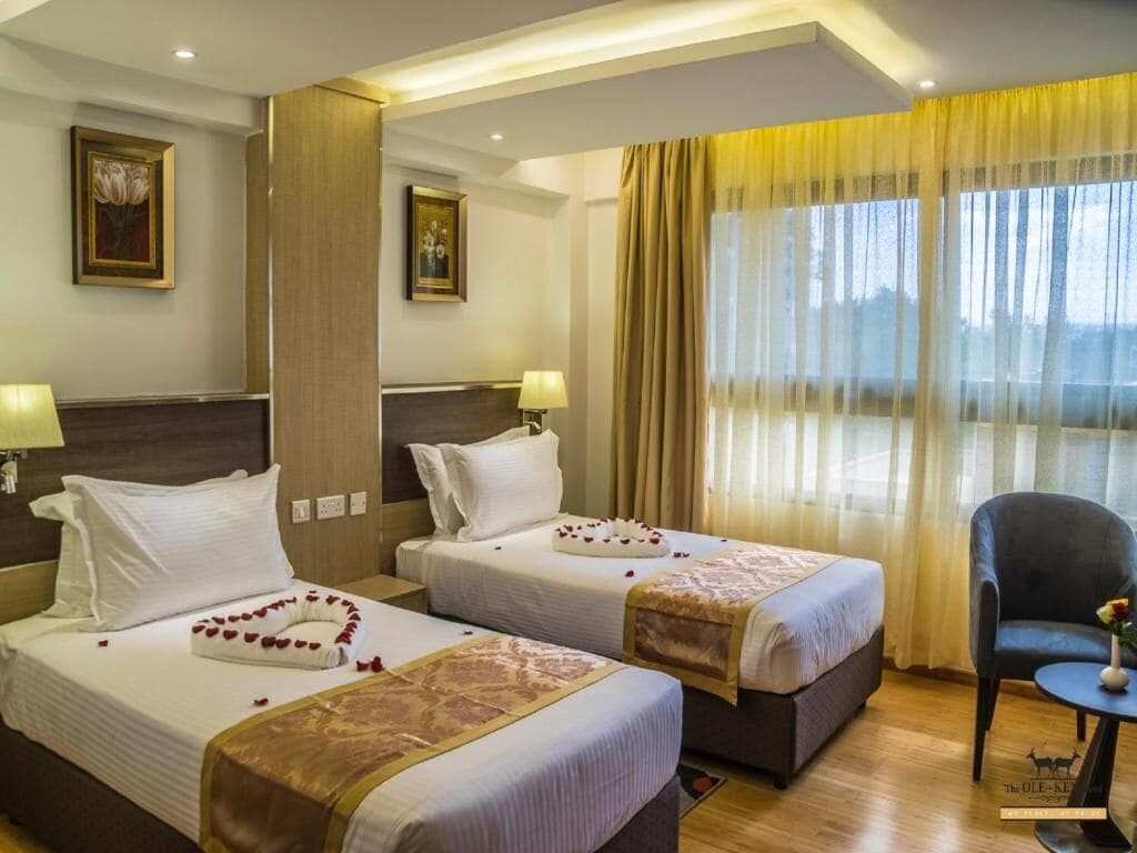 Quarto de hotel com duas camas, um espaço para sentar e vista para o exterior.