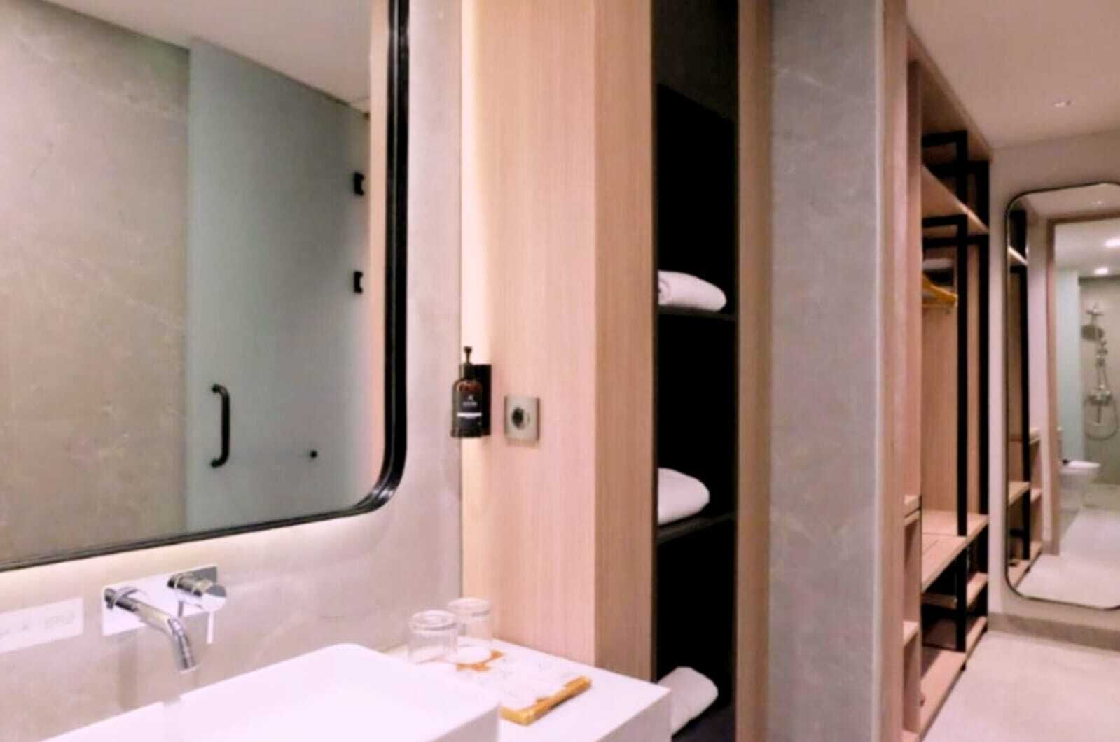 Uma casa de banho moderna com um espelho grande, uma sanita branca e uma área de duche.