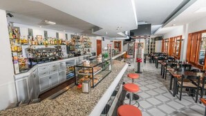 Uma área de bar com balcão, banquetes e diversas garrafas e copos.