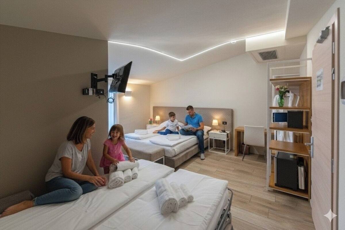 Quarto de hotel moderno com duas camas, uma televisão e uma pequena área de escritório.