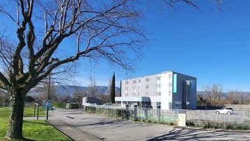 Um edifício moderno com telhado plano, janelas amplas e uma placa indicando que é um hotel.