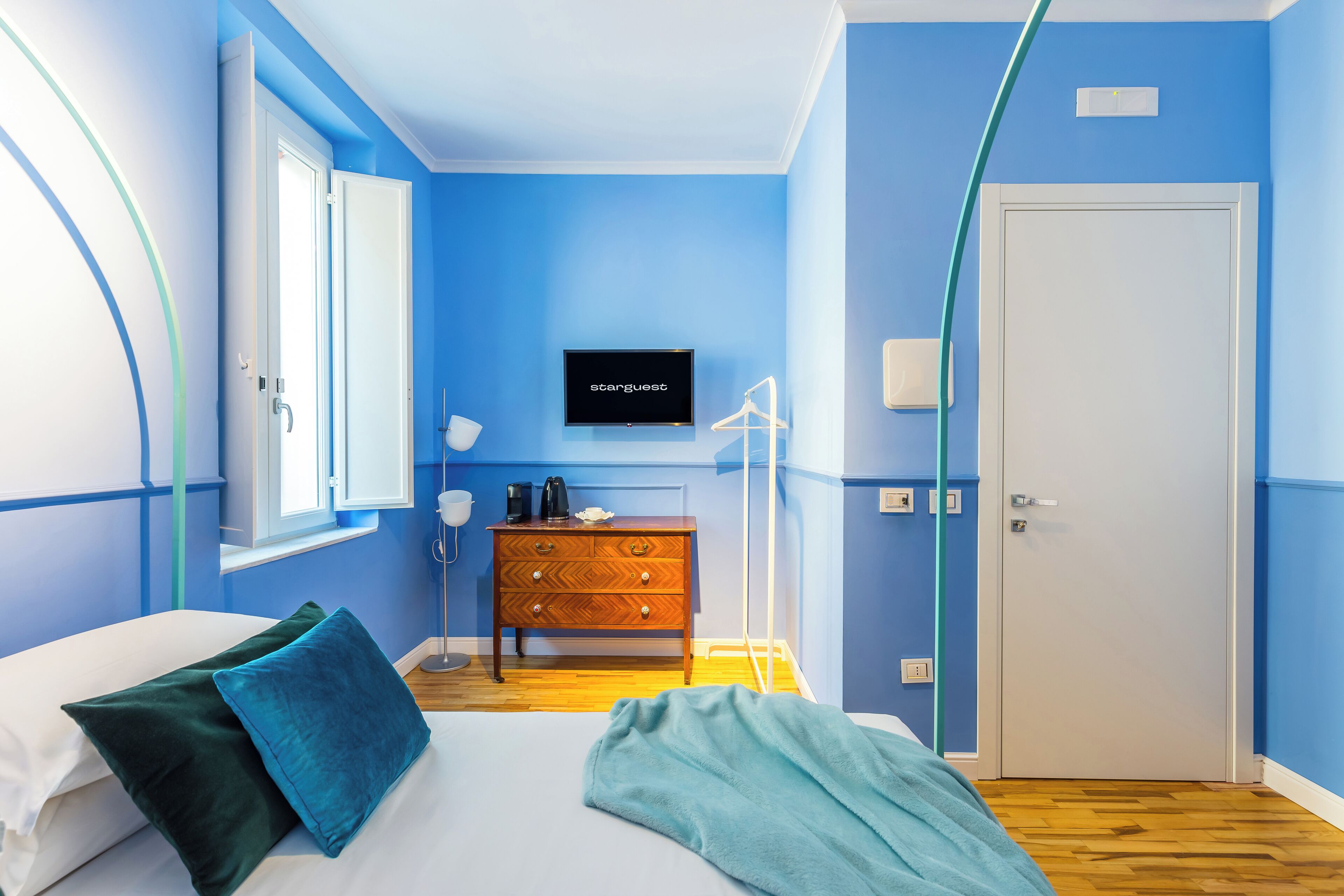 Quarto com cama, cômoda, televisão e porta.
