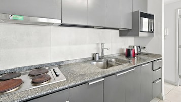 Cozinha moderna com armários cinza, uma pia de aço inoxidável, uma torradeira e uma chaleira.