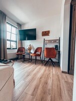 Uma sala de estar moderna com televisão de tela plana, duas poltronas de couro, uma mesa de centro e uma placa de madeira na parede.
