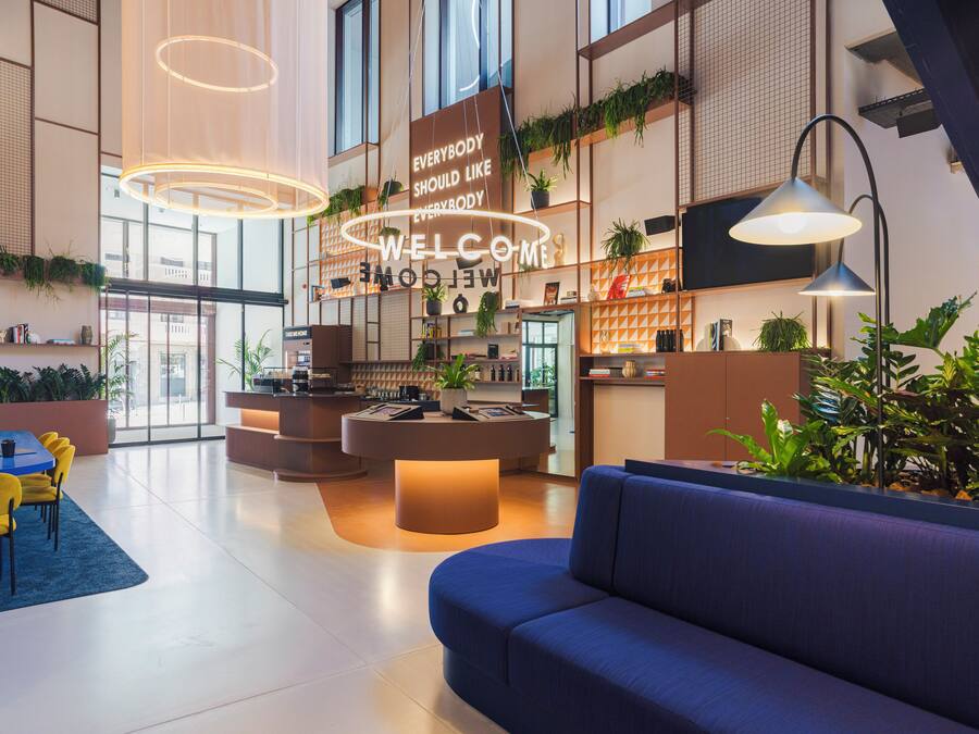 Um hall moderno com um sofá azul, um balcão de recepção e uma área de estar circular.